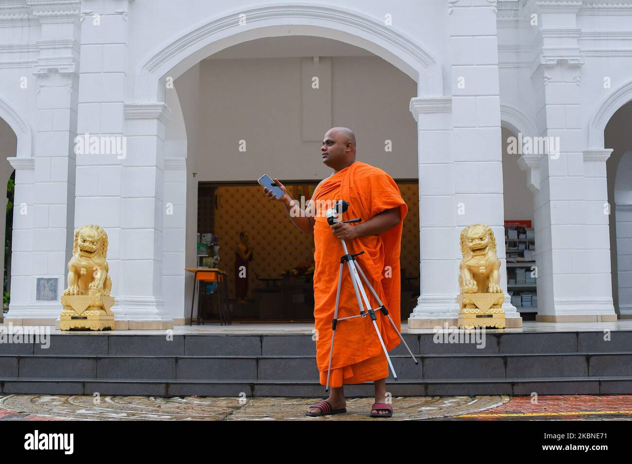 A Buddhist monk holds a tripod before a special Vesak day prayer at a ...