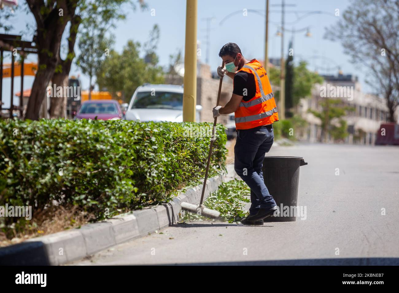 A municipal worker, wearing a face mask, cleans a main street in the ...