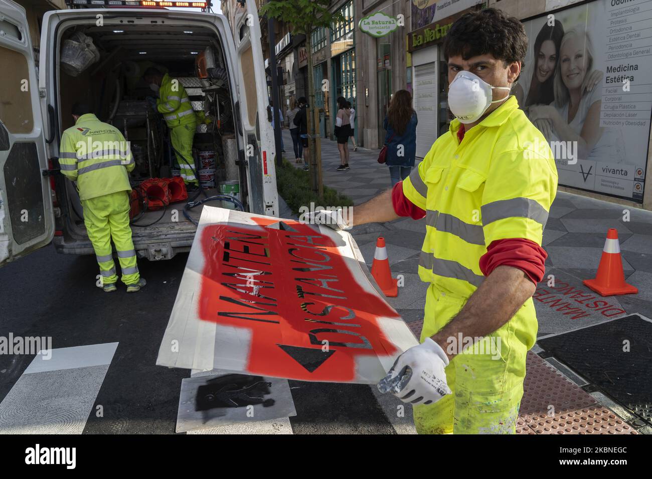 Municipal workers paint the slogan “Keep your distance” on the city's ...