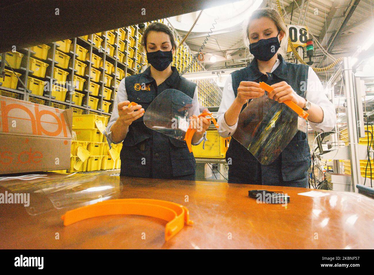 Two workers assemble plastic face shields at Igus plastic factory in ...