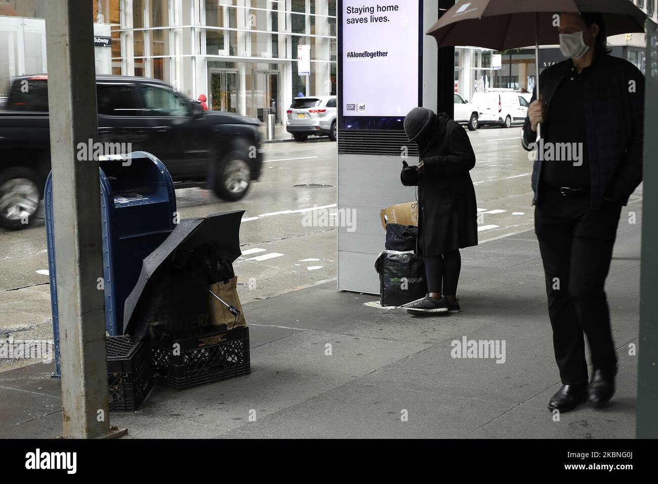 A homeless person looks her telephone at a charging station in New York ...