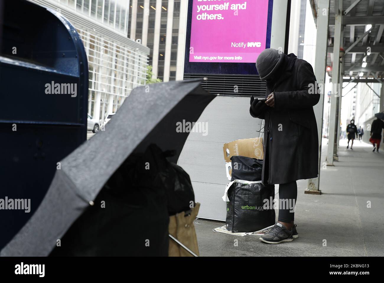 A homeless person looks her telephone at a charging station in New York ...