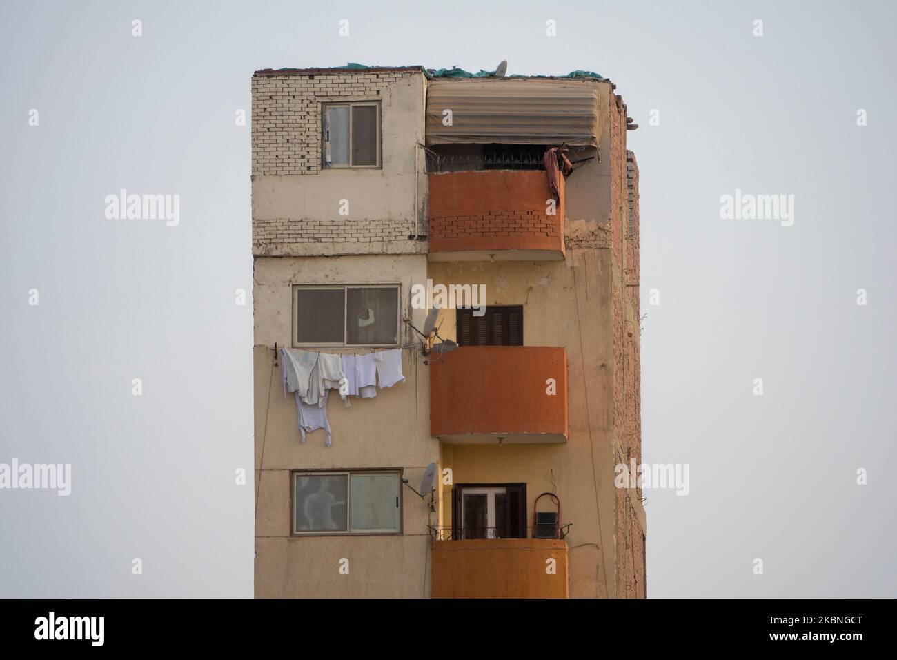 Close up top section of apartment block building with bricks, balconies ...