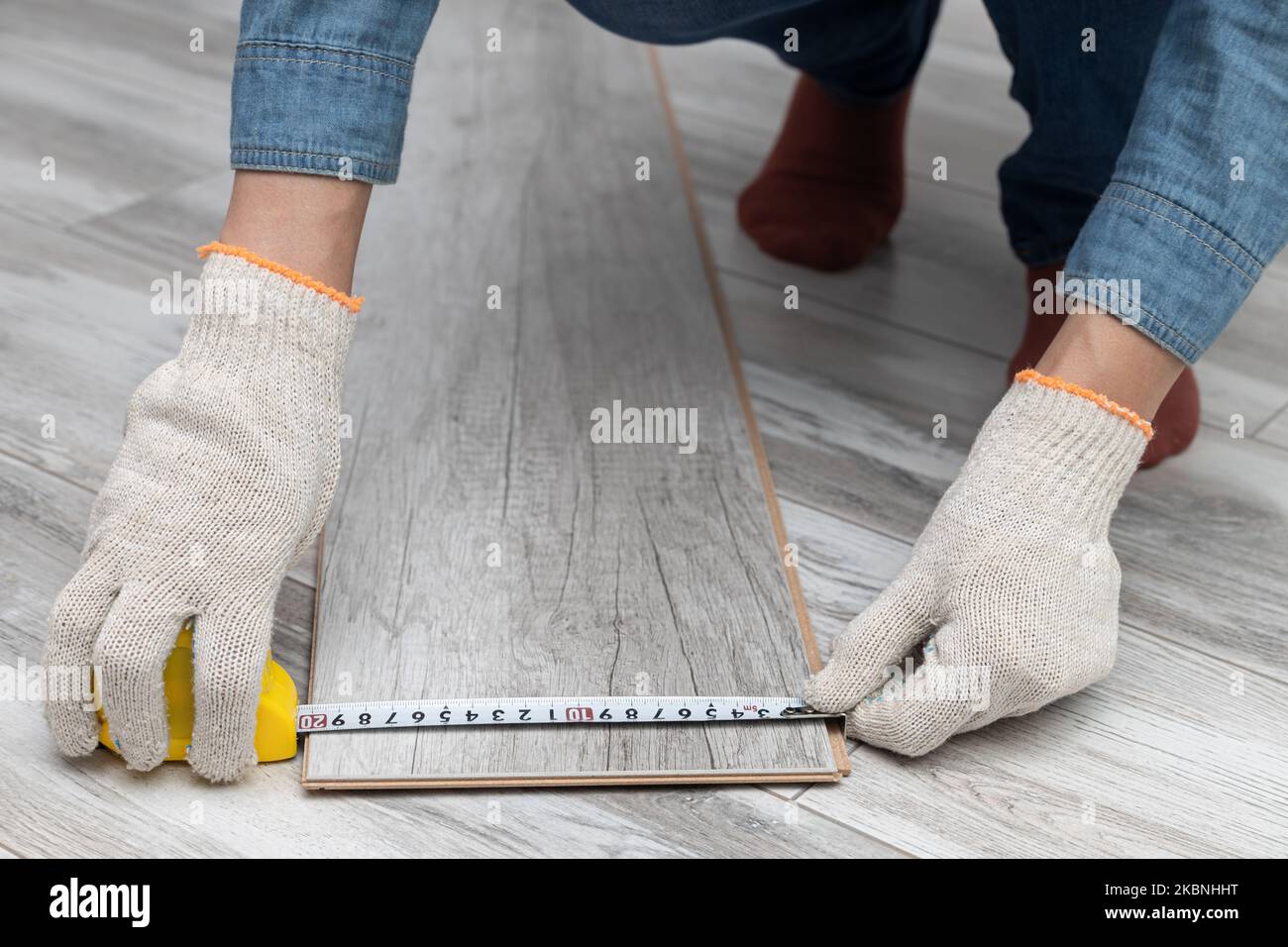 a woman measures the width of a board with a tape measure Stock Photo ...