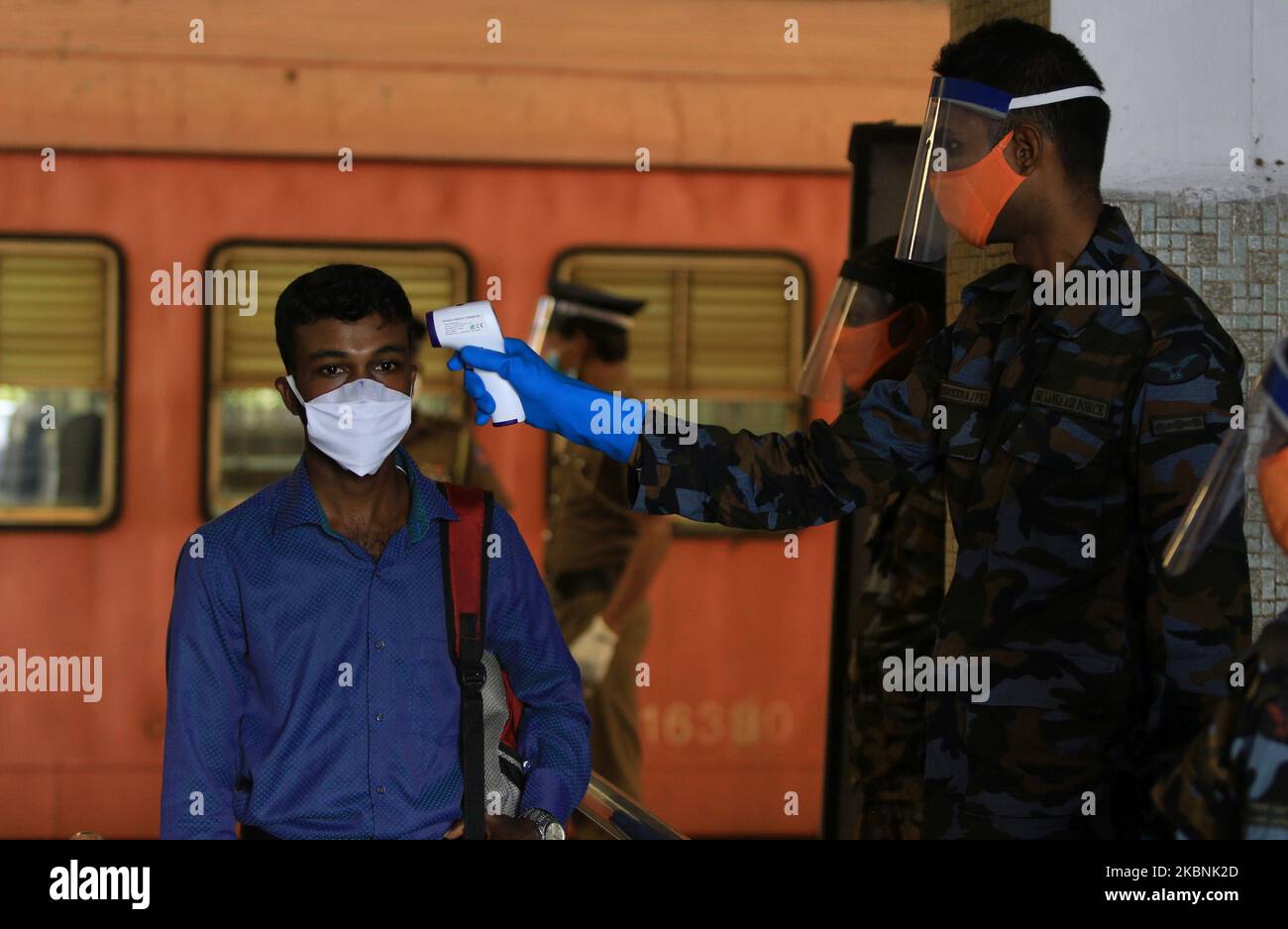 A Sri Lankan soldier conducts a temperature check on a commuter who arrived for work at Colombo ...