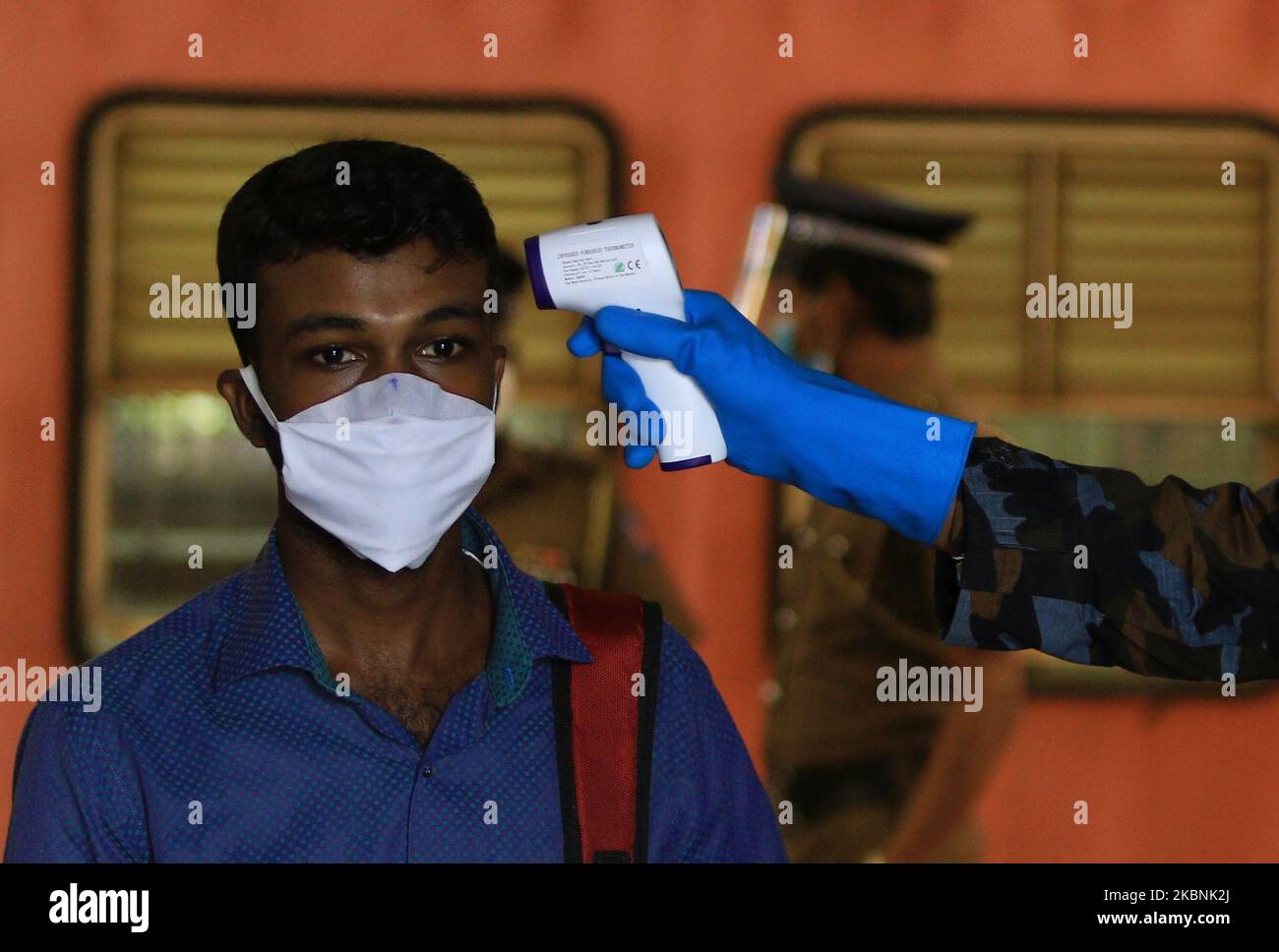 A Sri Lankan soldier conducts a temperature check on a commuter who arrived for work at Colombo ...