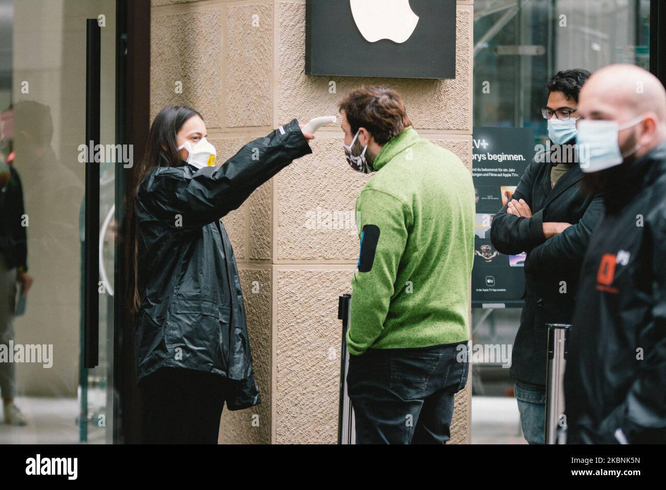 A staff checks body temperature of customer before entering the Apple ...