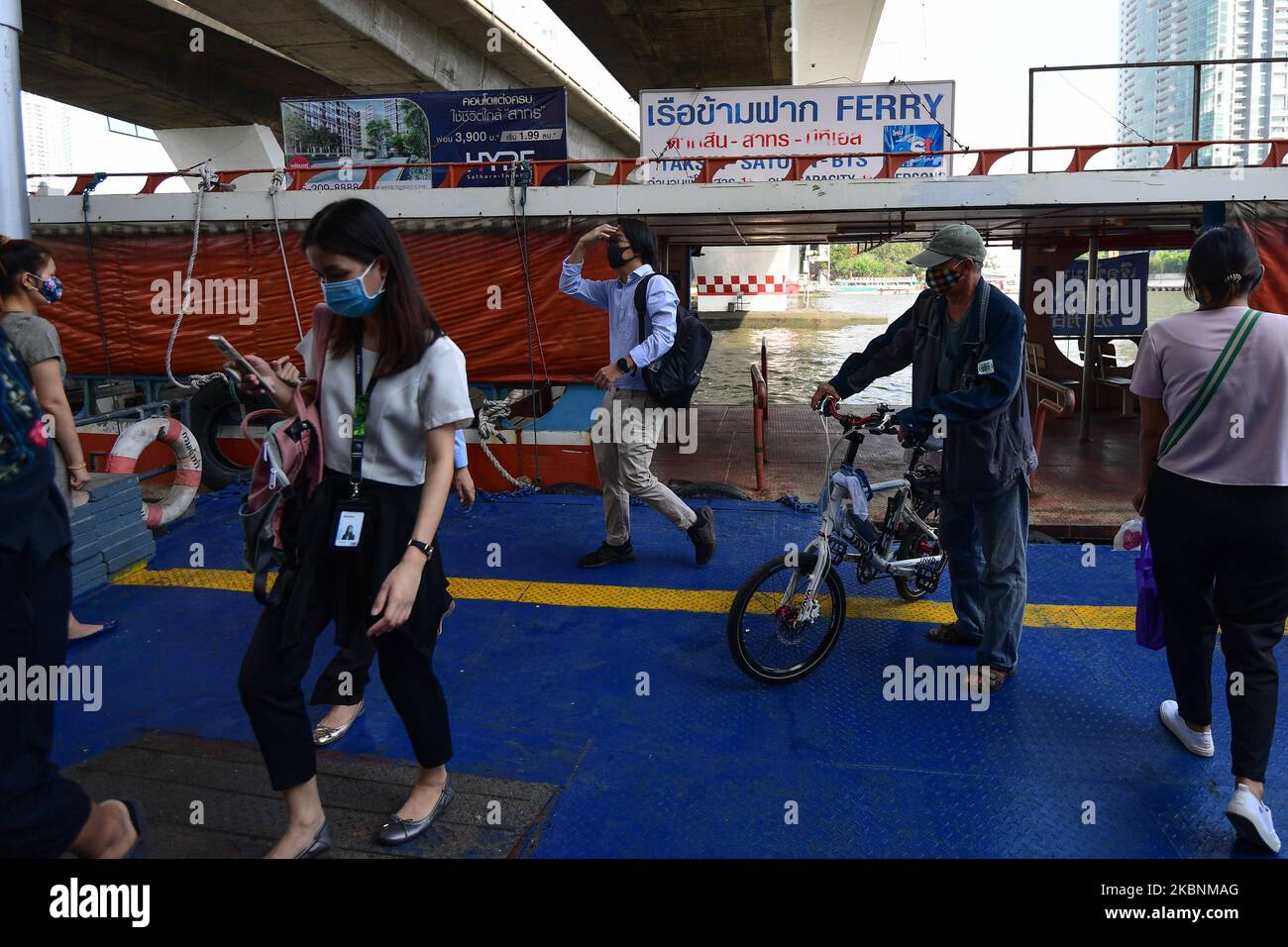Passengers wear face masks disembarking from the Chao Phraya Ferry Boat ...