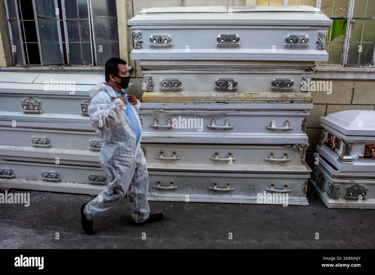 A funeral worker takes off his personal protective equipment (PPE ...