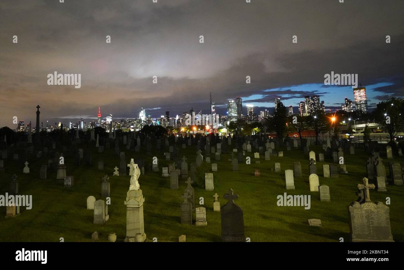 Tombstones are seen in a New York City cemetery against the background ...