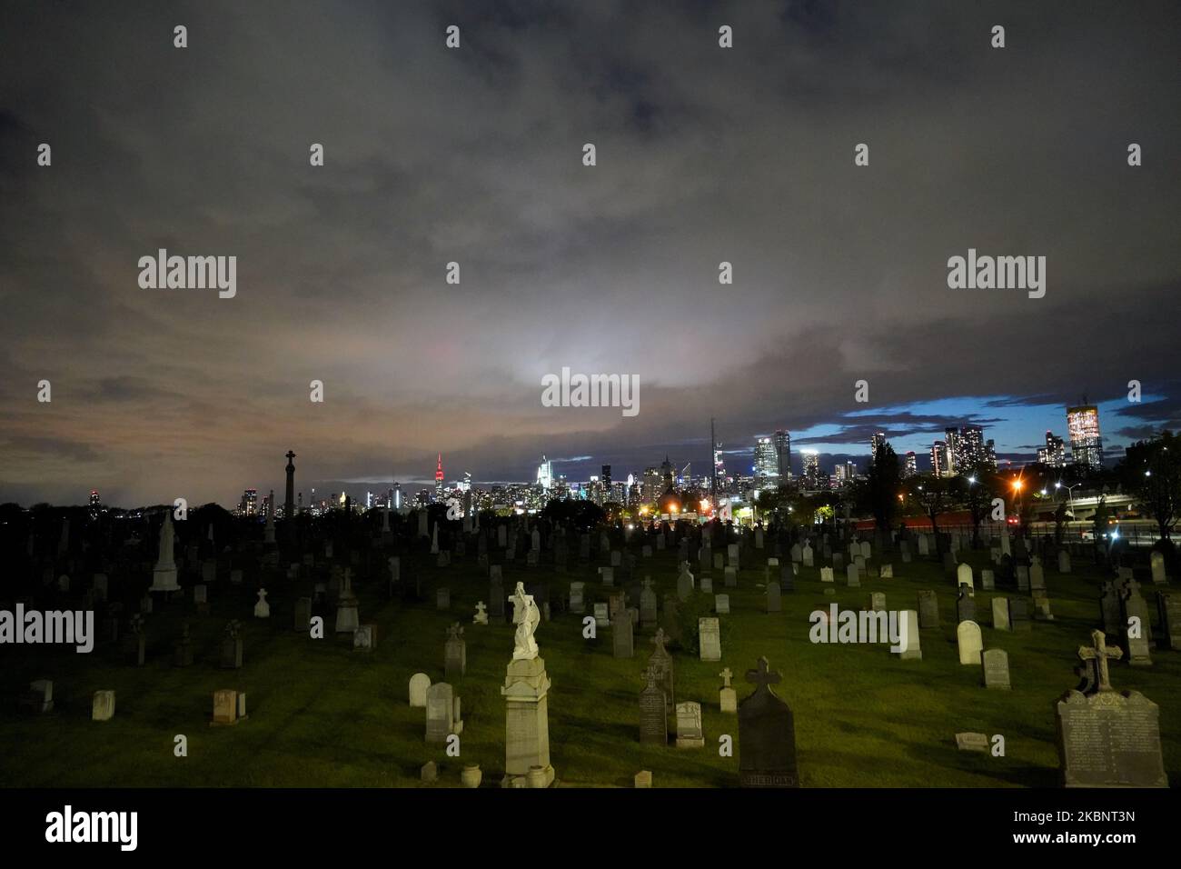 Tombstones are seen in a New York City cemetery against the background ...