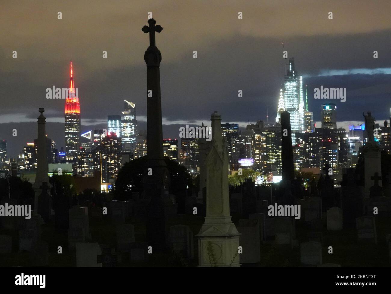 Tombstones are seen in a New York City cemetery against the background ...