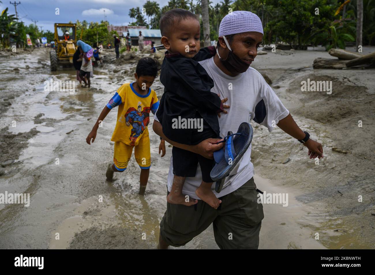 Residents crossed the road that was buried by mud due to flash floods ...