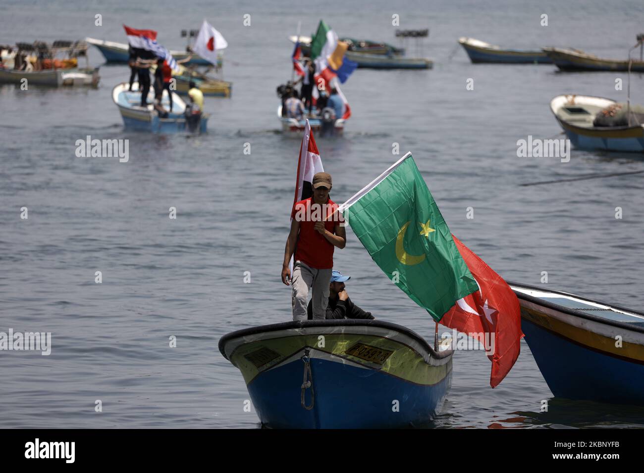 Palestinians ride boats and wave flags of various countries during an ...