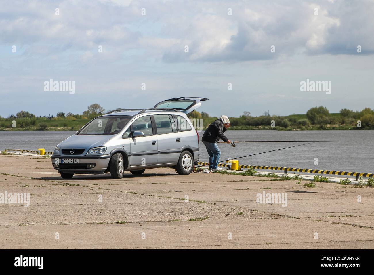 Angler fishing on the concrete Vistula (Wisla) river embankment with ...
