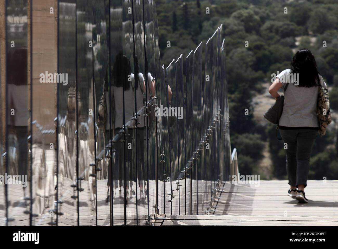 A woman walks next to a divider made of plexiglass at the entrance of ...