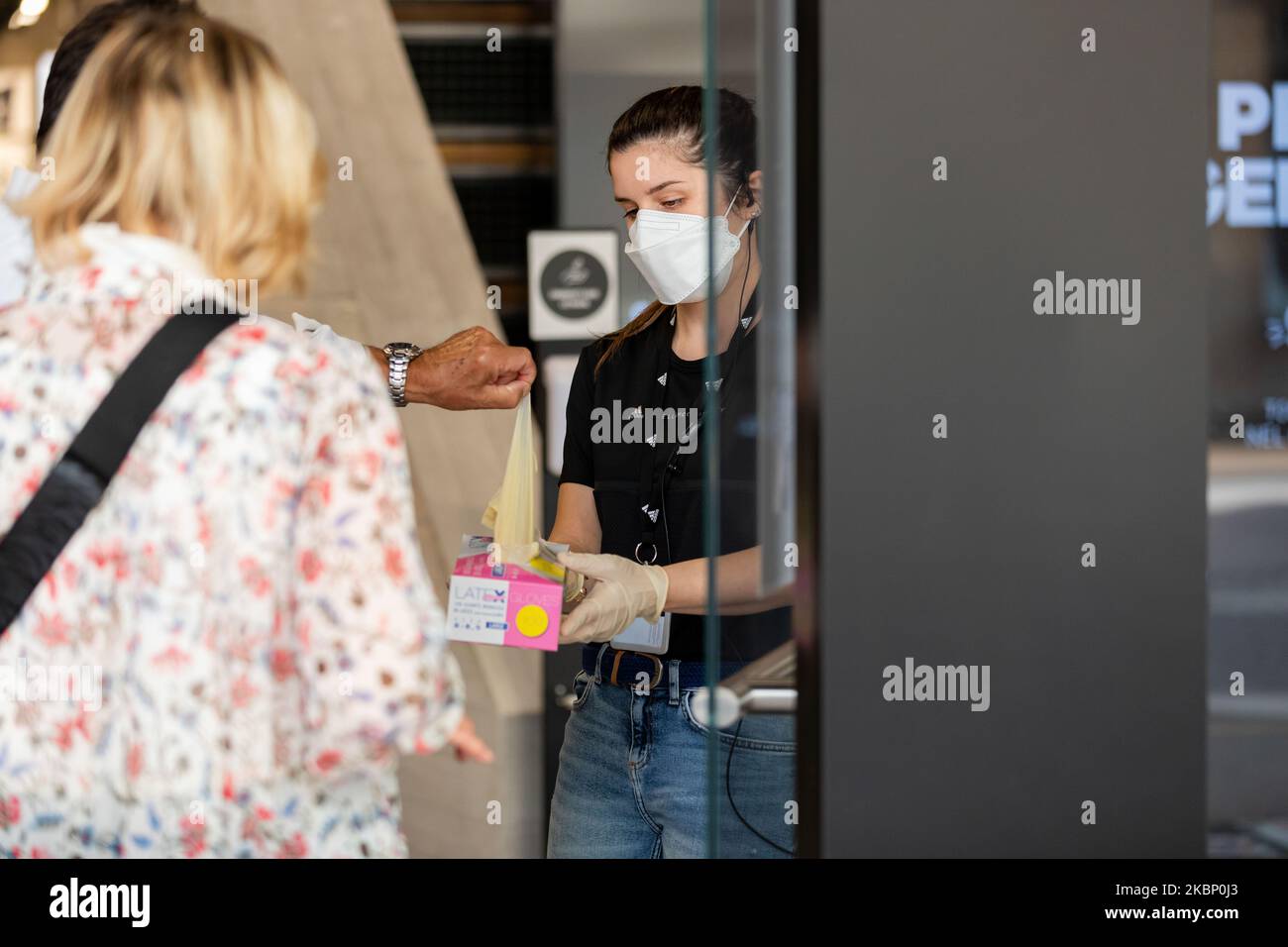 Staff members give hand-sanitizing gel and test customer’s temperature ...