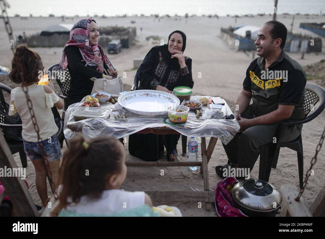 A palestinian family wait to have their Iftar breaking a Ramadan fasting day on the beach of ...