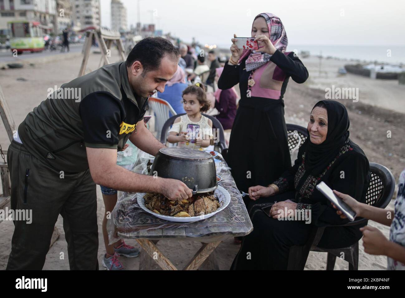 A palestinian family wait to have their Iftar breaking a Ramadan fasting day on the beach of ...