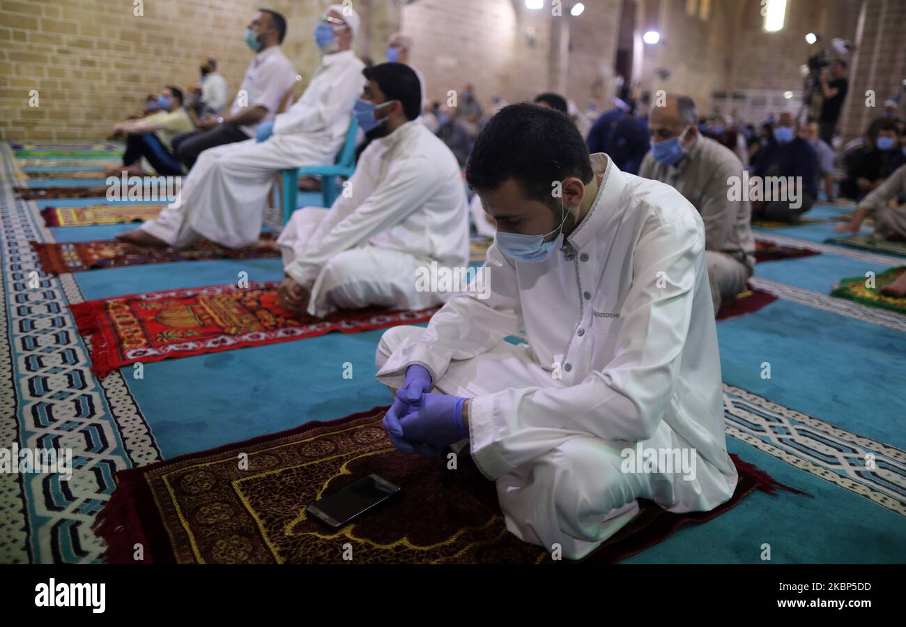 Palestinians wearing masks attend Friday prayers in a mosque as the ...
