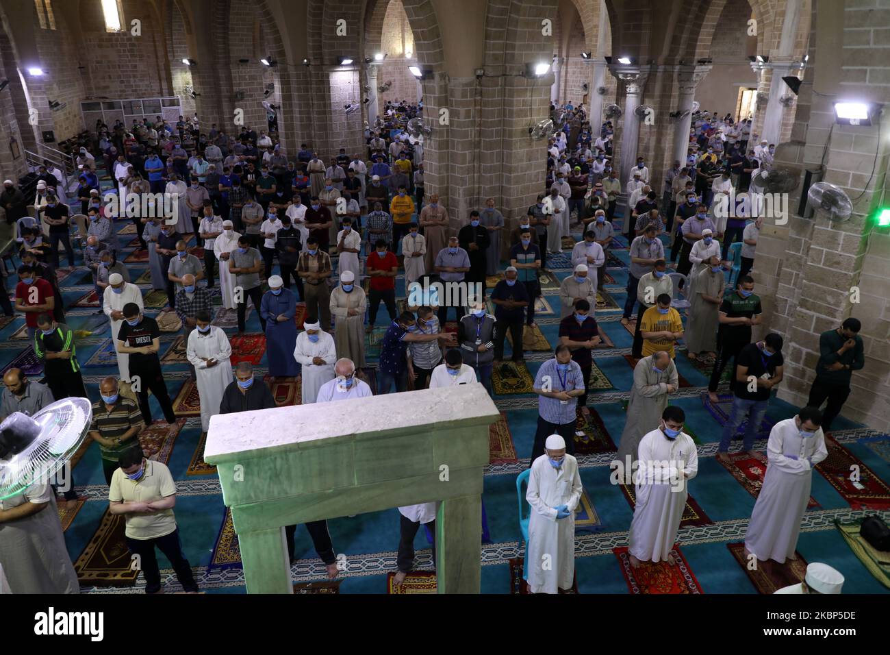 Palestinians wearing masks attend Friday prayers in a mosque as the ...