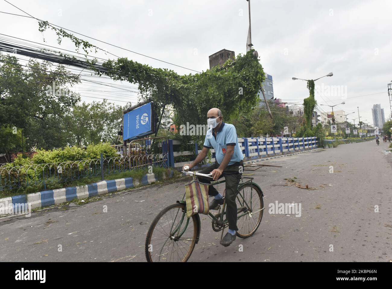 A man with a bicycle passes by a damaged lamp post due to Amphan super ...
