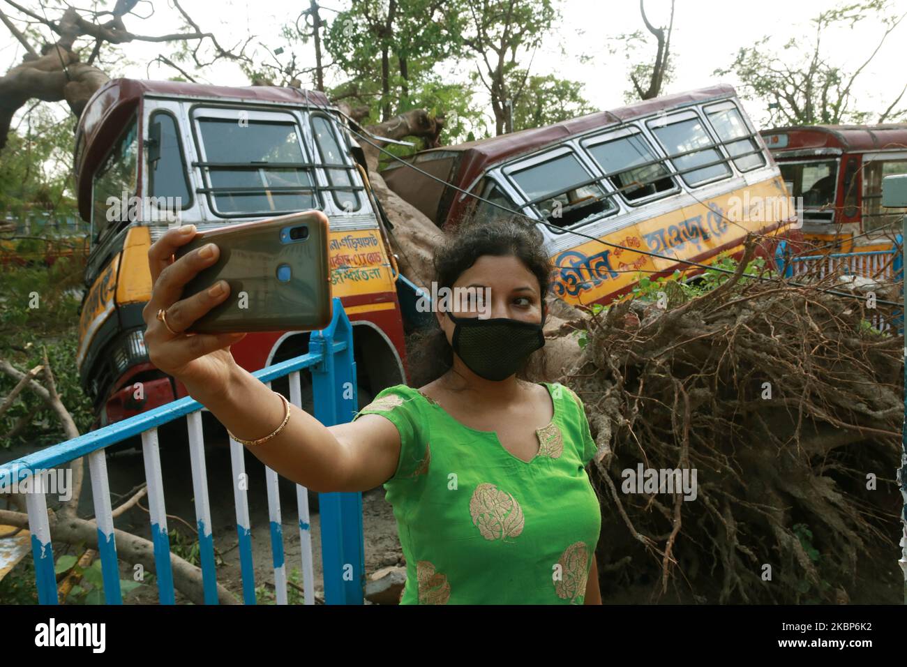 A women mobile selfie at front of A Passenger bus damaged by a fallen ...