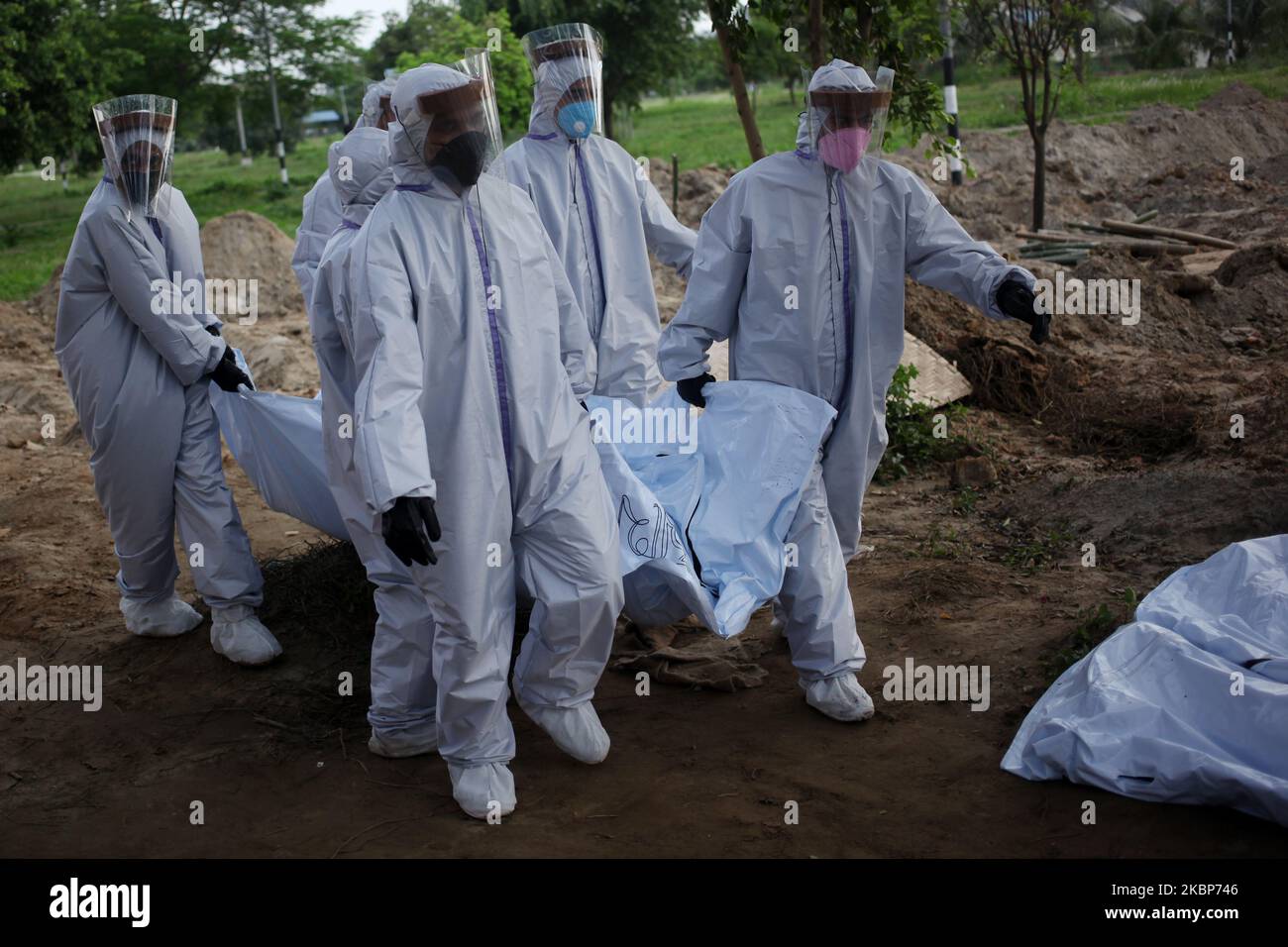 Workers carry a COVID-19 patient's dead body to the grave for funeral ...