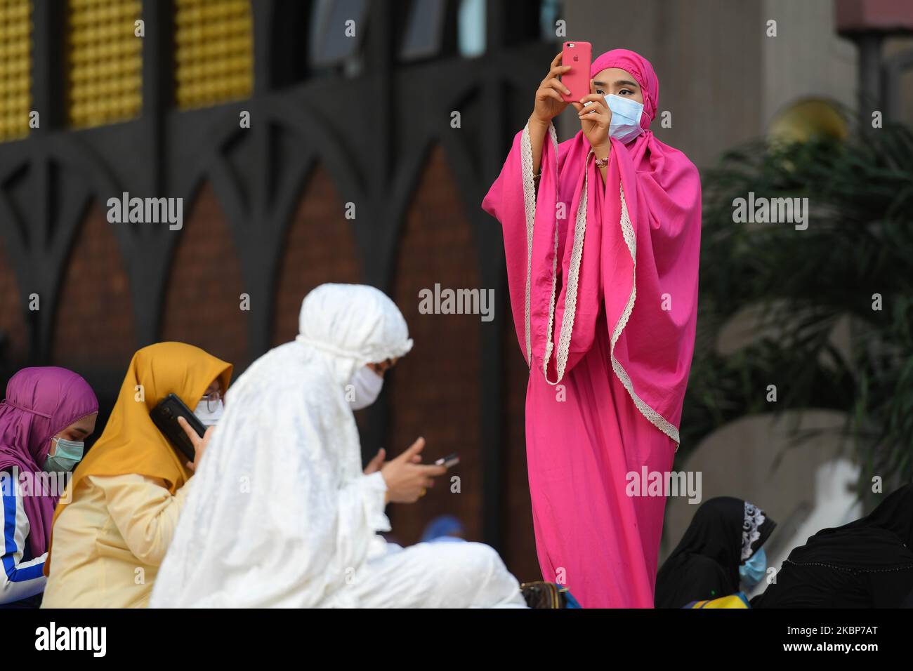 Muslim woman is seen wearing a face mask take a photo before offer ...
