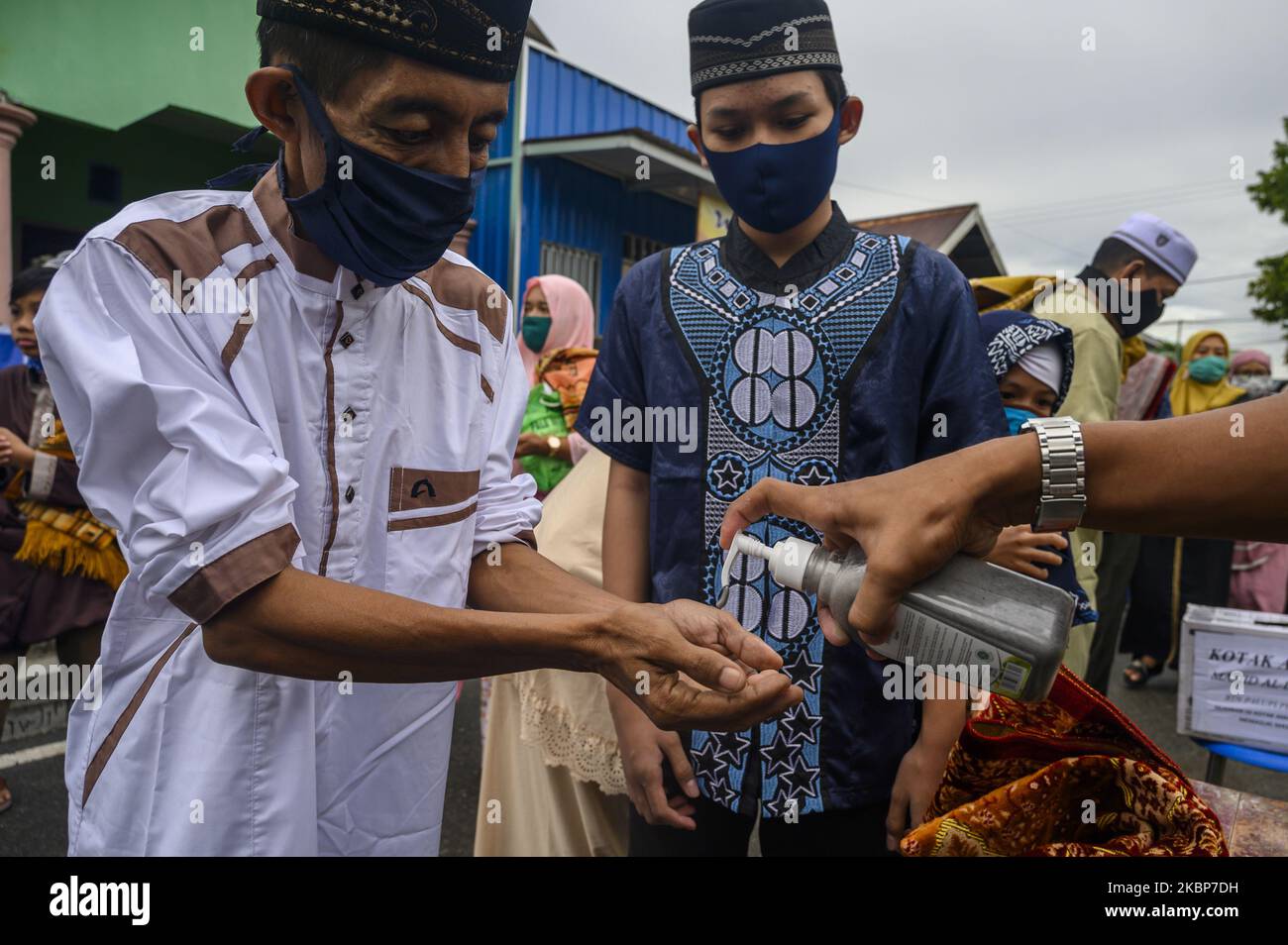 Muslims stand in line to wash their hands with cleaning fluid before ...