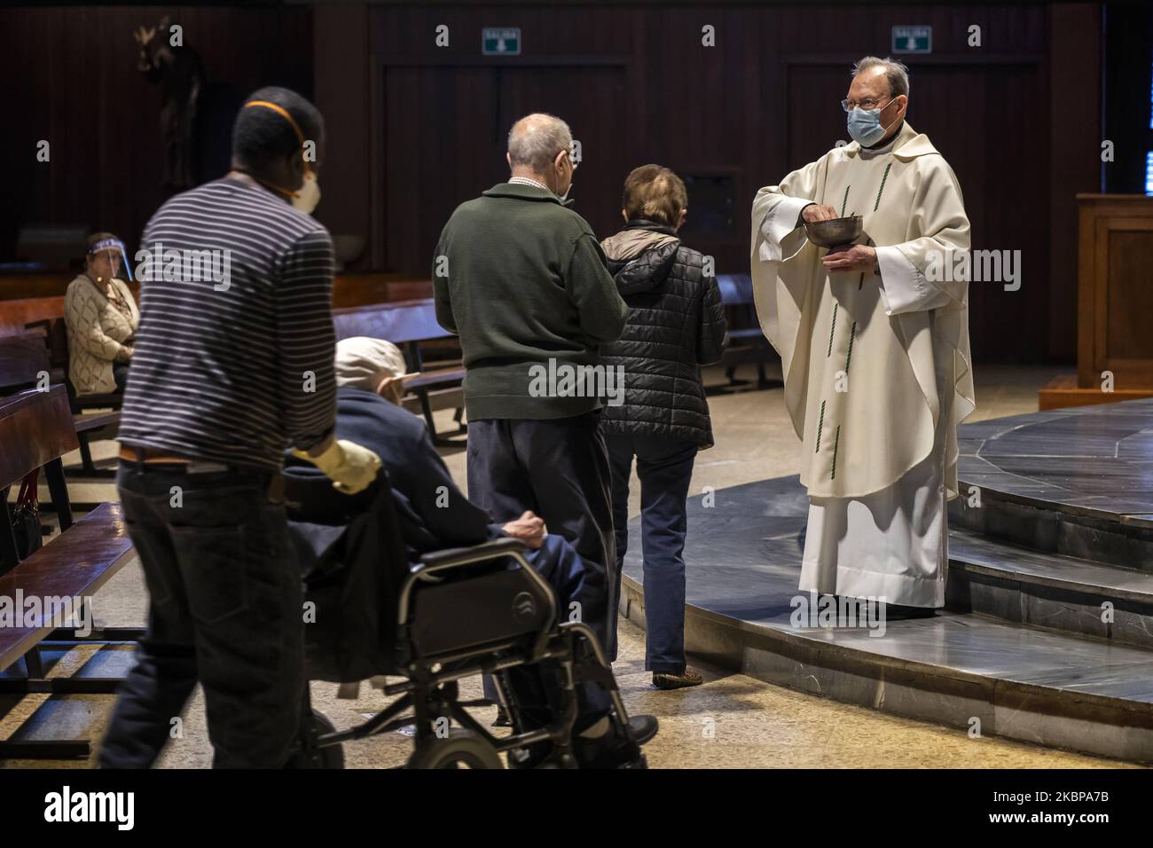 A priest giving communion to some parishioners in Santander, Spain, on ...