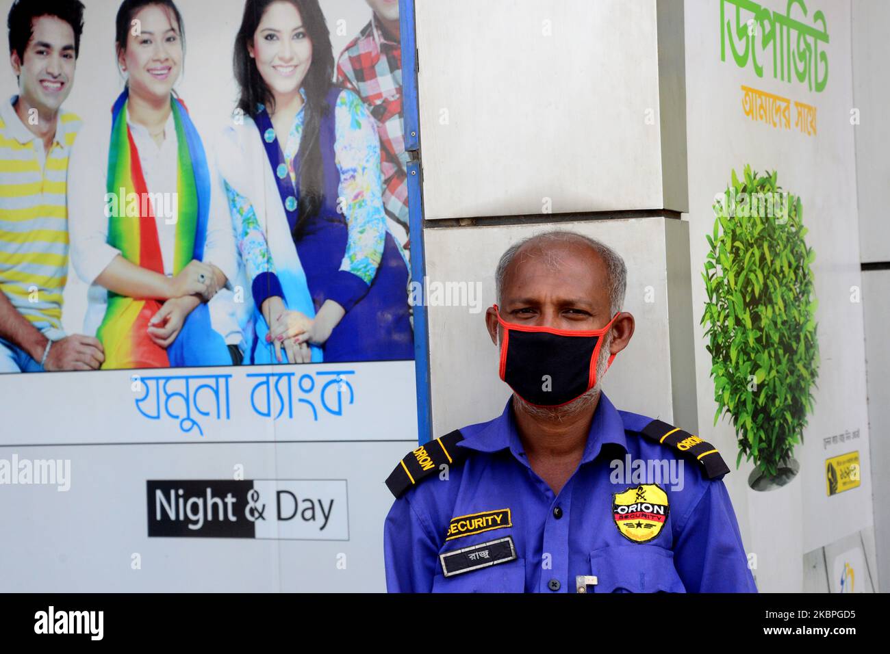 A private security guard at an ATM booth wearing a facemask as a ...