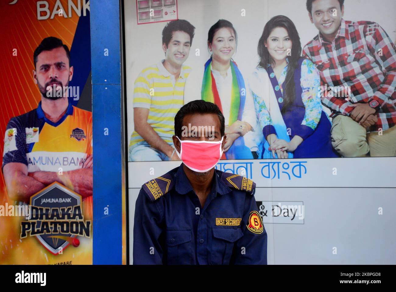 A private security guard at an ATM booth wearing a facemask as a ...
