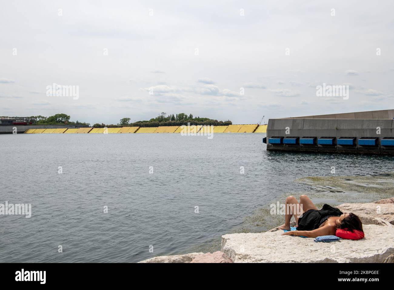 A lady sunbathing in front of the MOSE Barriers, at Alberoni, Lido of ...