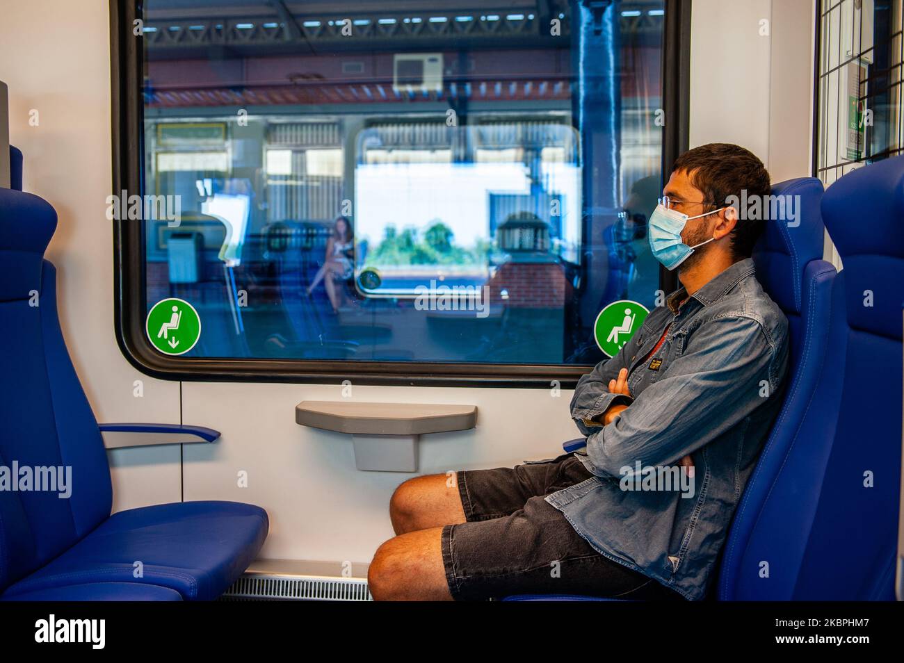 A man is sitting on the train wearing a mouth mask, during the first ...
