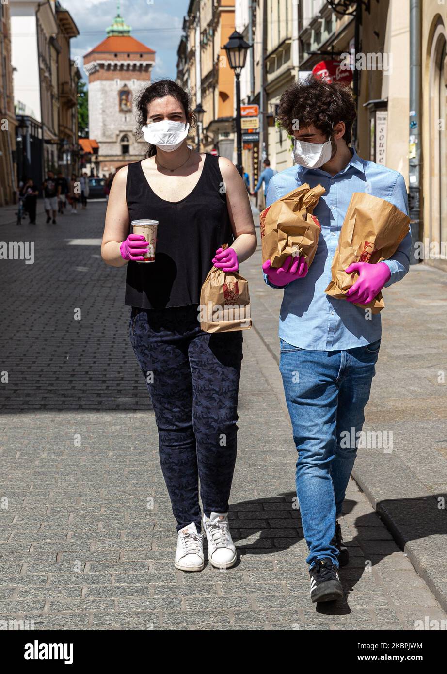 A man and woman in a face protective mask and gloves are seen walking ...