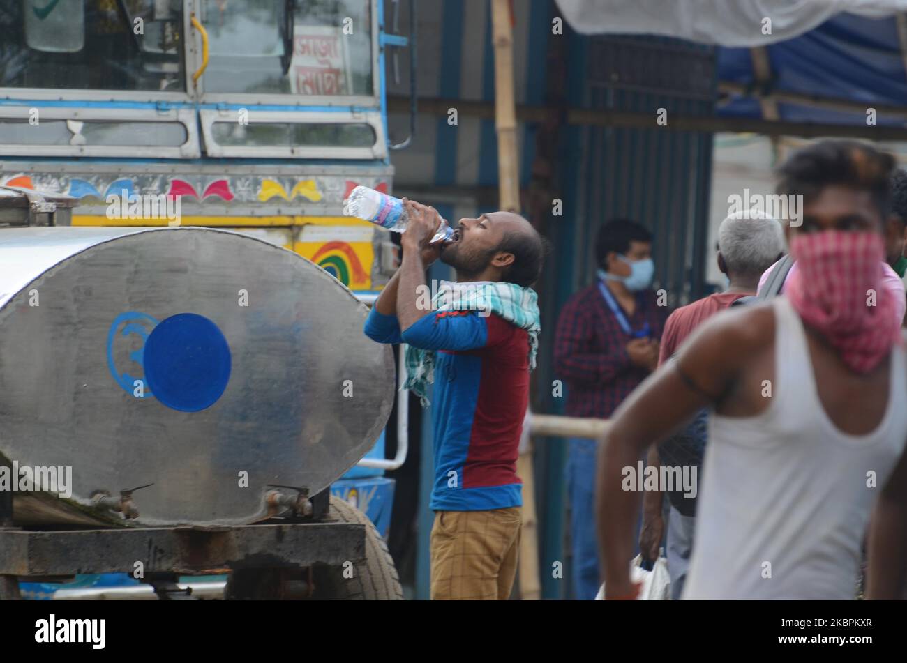 Migrant labourer drinks water during the waiting for a bus to go their ...