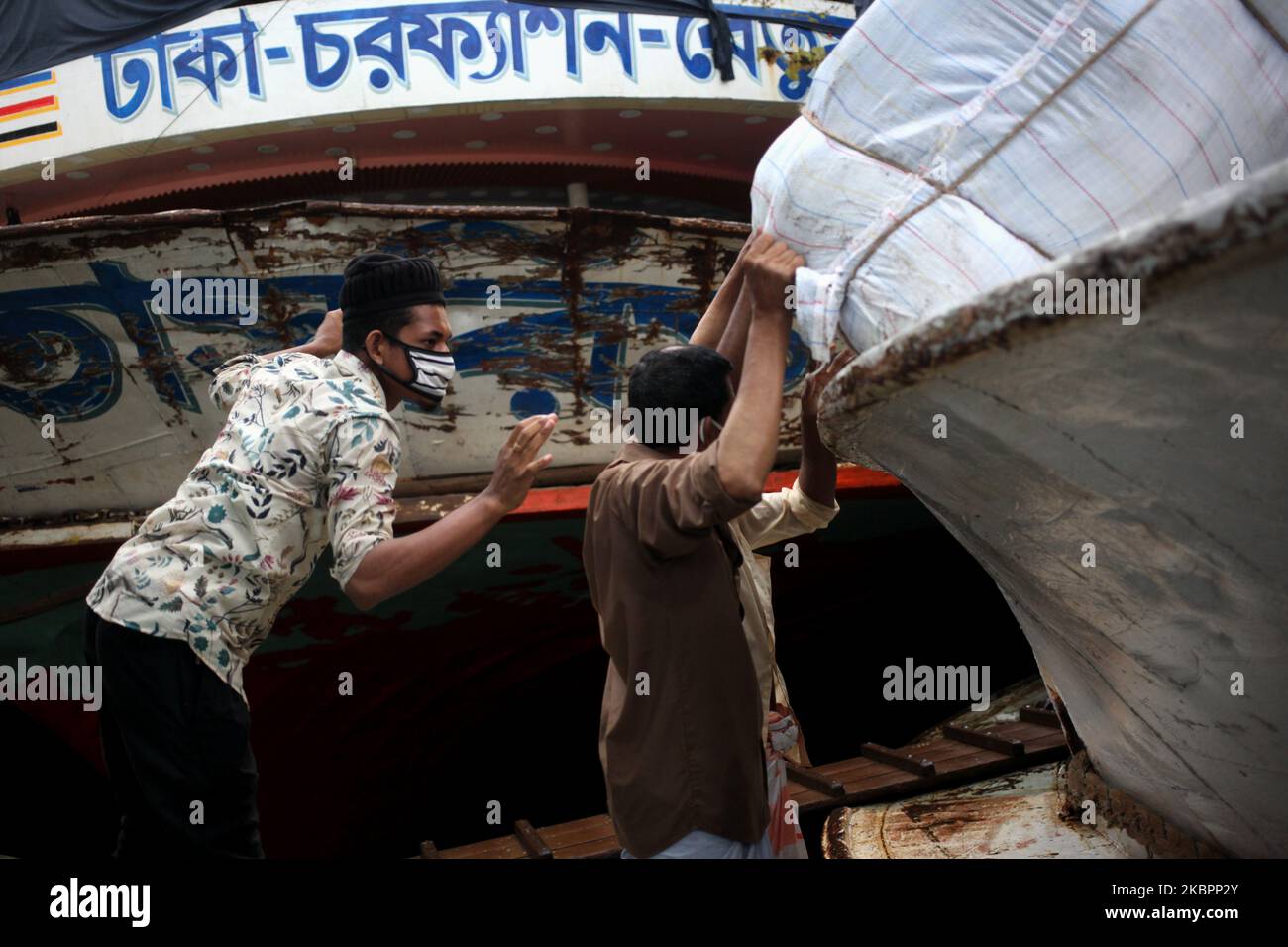 Laborers carry goods to a launch after the government-imposed lockdown at Sadarghat launch ...