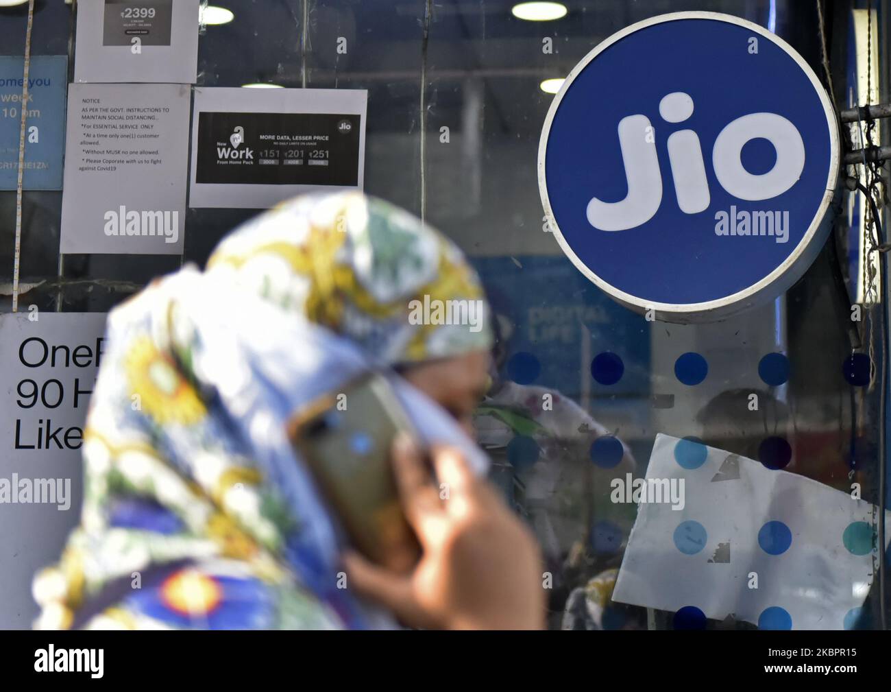 A woman on a mobile passes by a Jio store in Kolkata, India, 05 June ...