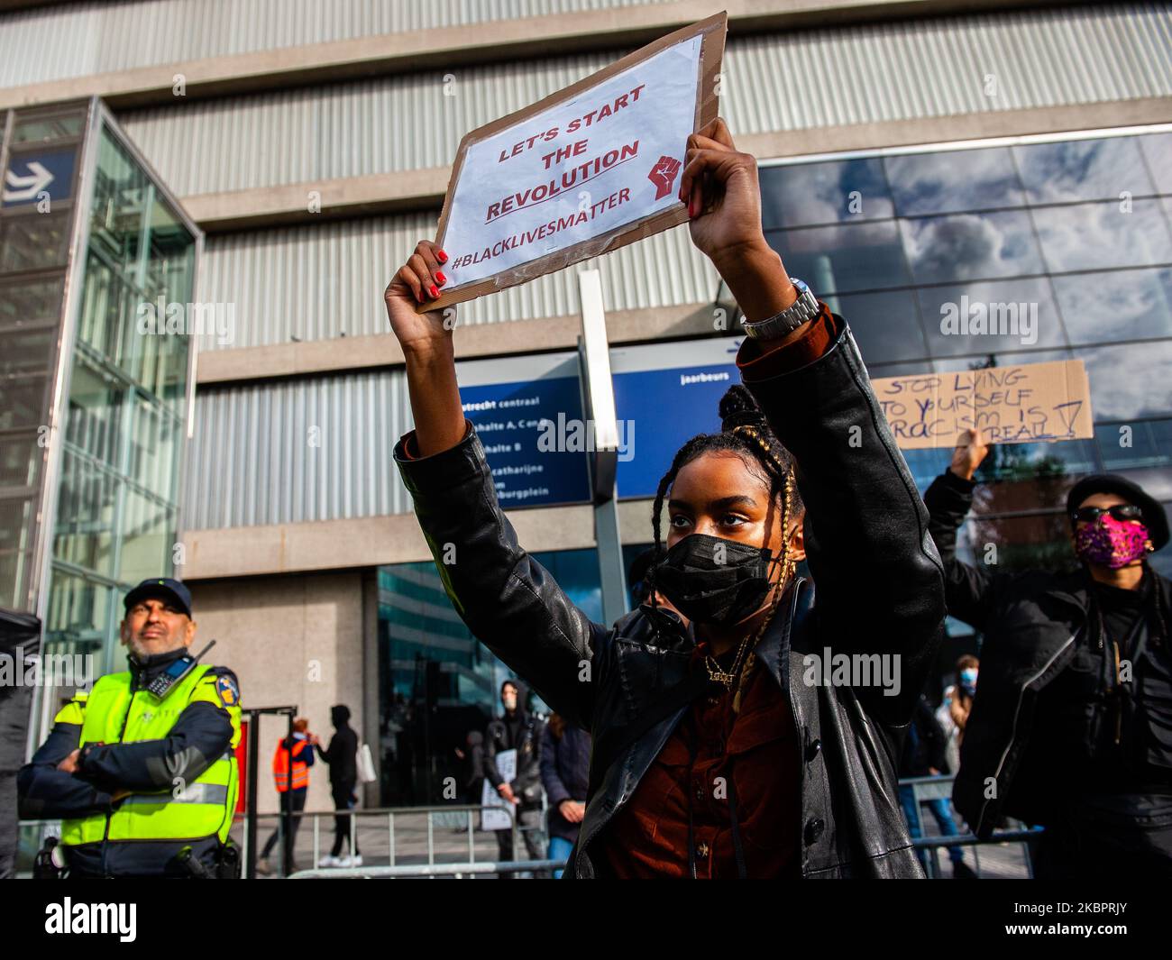 A black woman is holding an anti racist placard close to the police ...