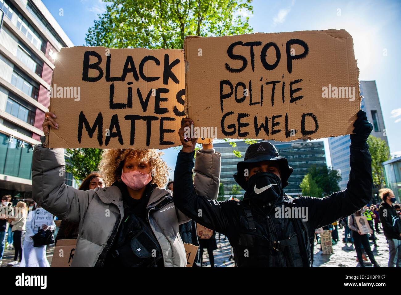 Two people are holding anti racist placards over their heads, during ...