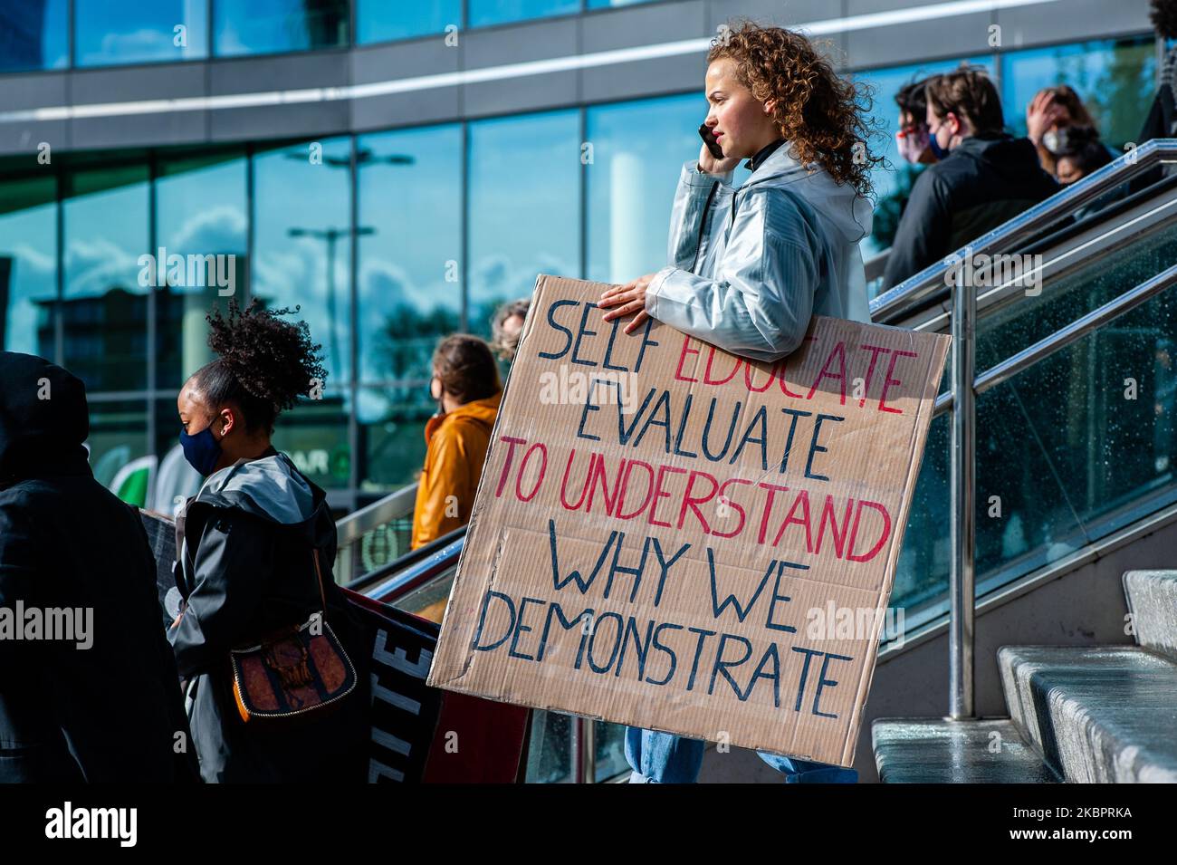 A woman is holding an anti racist placard while is downing the stairs ...