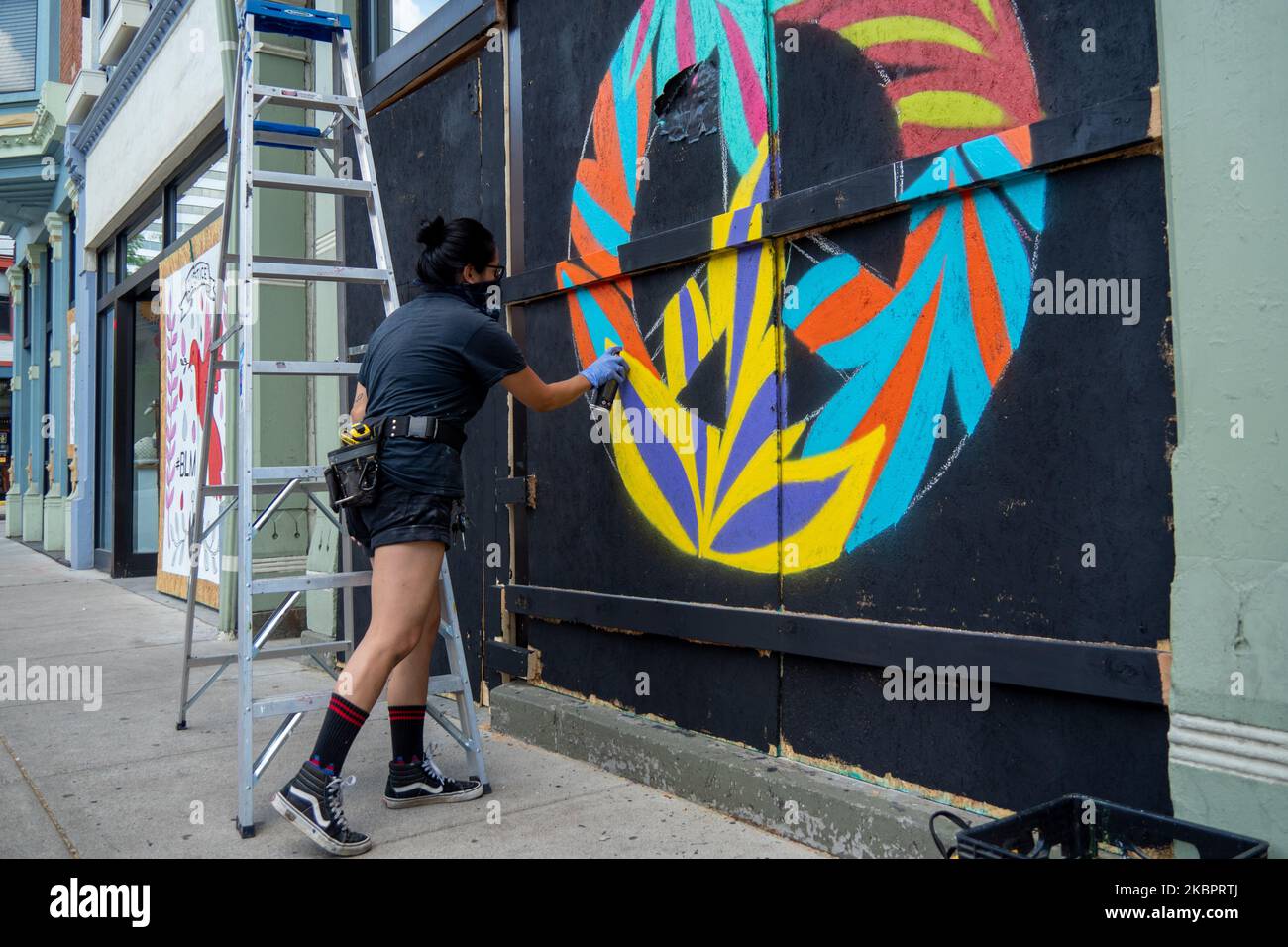 Jill Cleary paints a peace sign on plywood protecting The Little ...