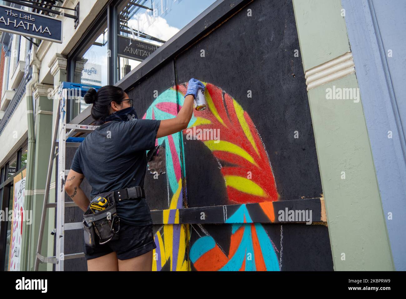 Jill Cleary paints a peace sign on plywood protecting The Little ...