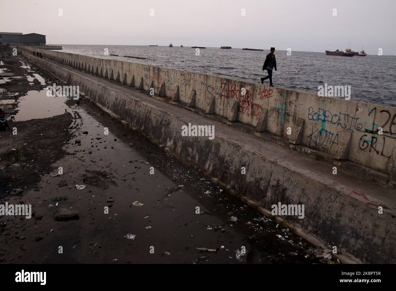 Residents walks on the giant sea wall embankment as the flood water ...