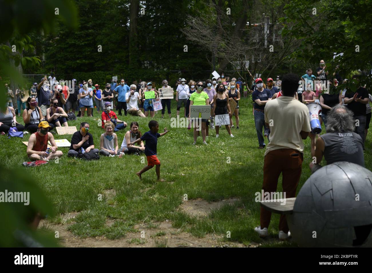 A young African-American boys walks around as community members gather ...