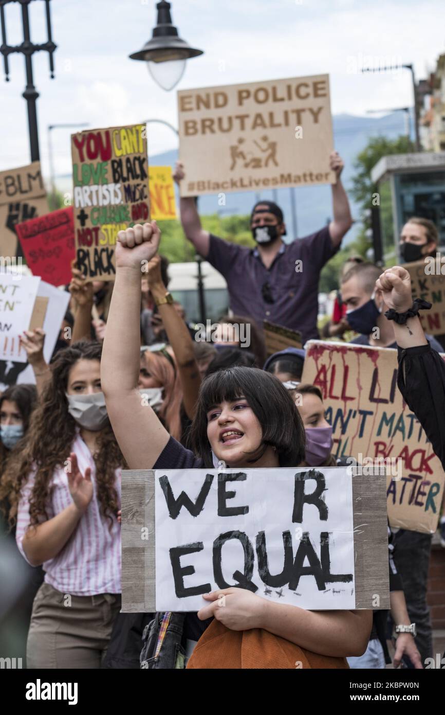 A woman holds a "We R Equal" sign during a Black Lives Matter and Roma ...