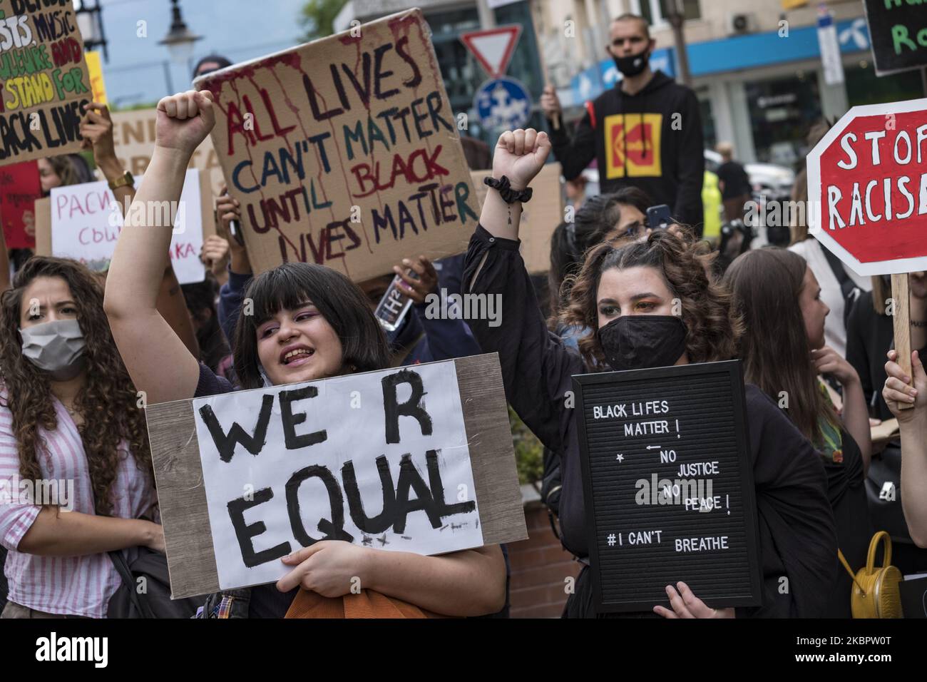 A woman holds a "We R Equal" sign during a Black Lives Matter and Roma ...