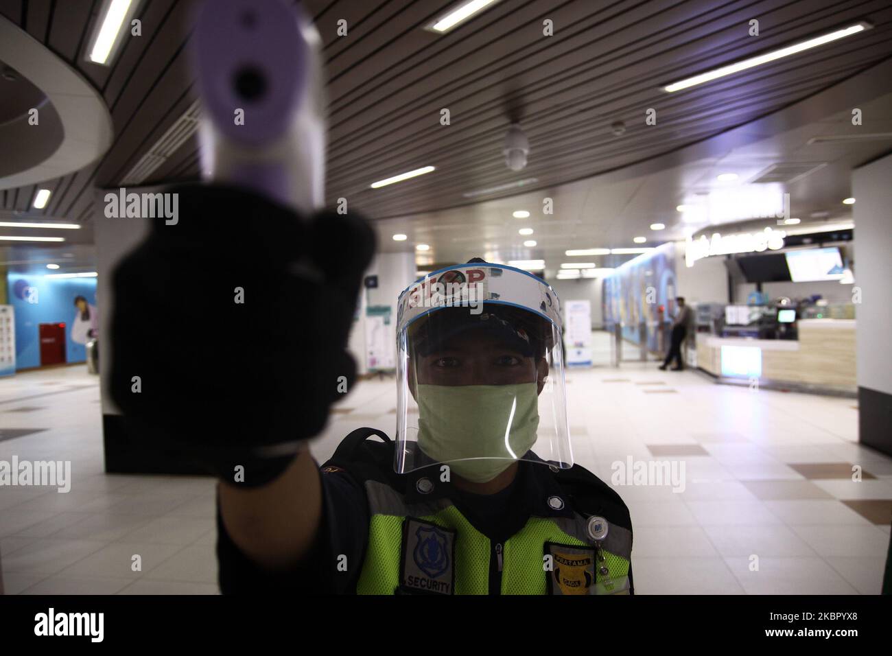 Indonesian security officer wearing face shield and mask checking the ...