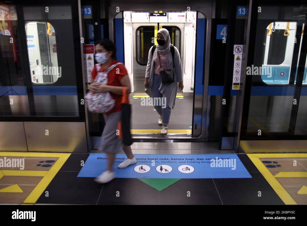 Passengers wearing protective face mask walks out from MRT Jakarta ...
